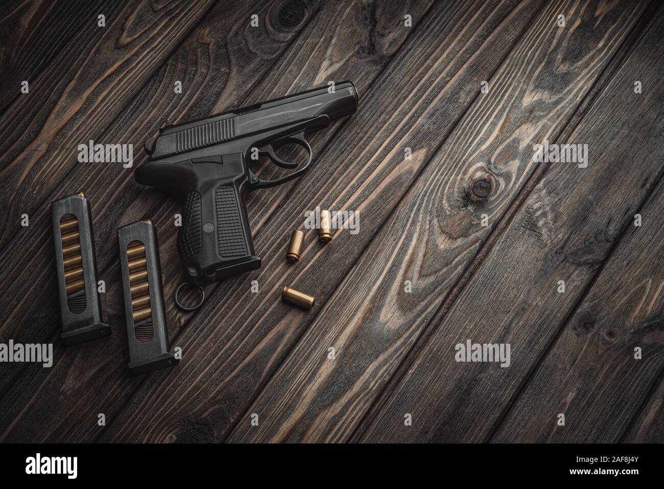 A modern black pistol and ammunition on dark wooden background. Weapons ...