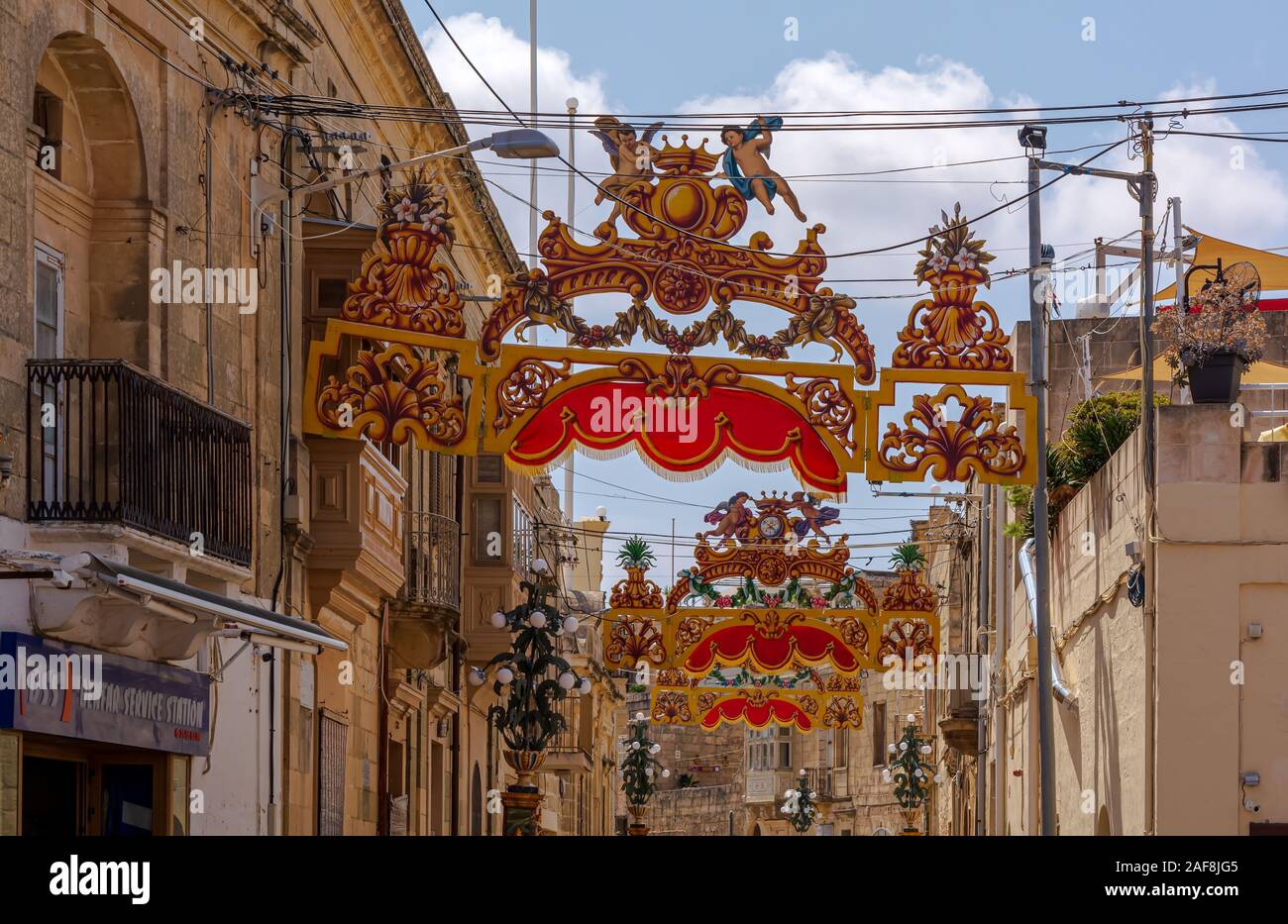 Charming street in Xaghra village, decorated with religious red banners ...
