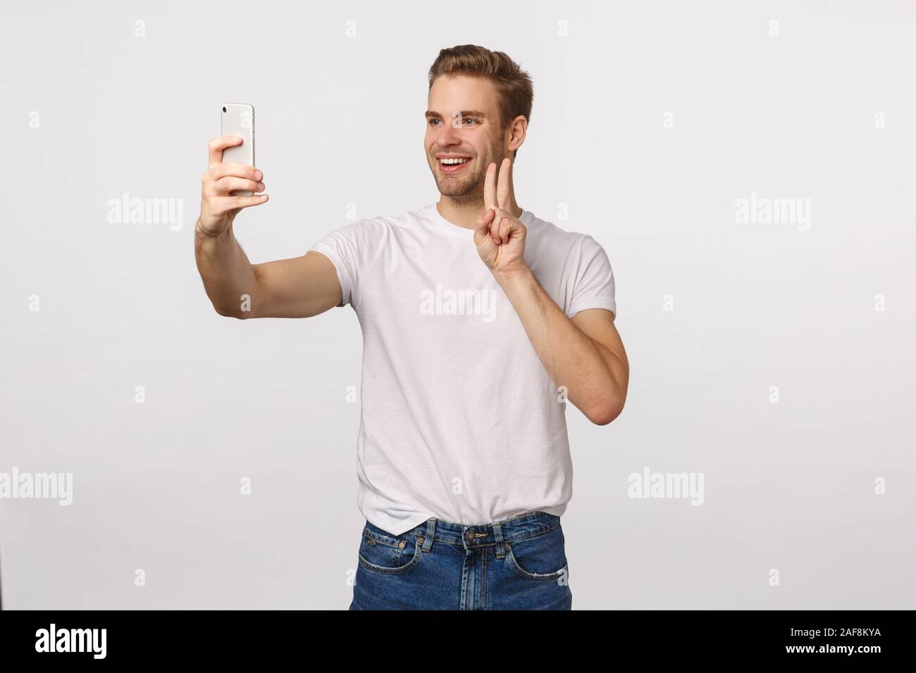 Cheerful man download new app, trying out cute filters as taking selfie ...