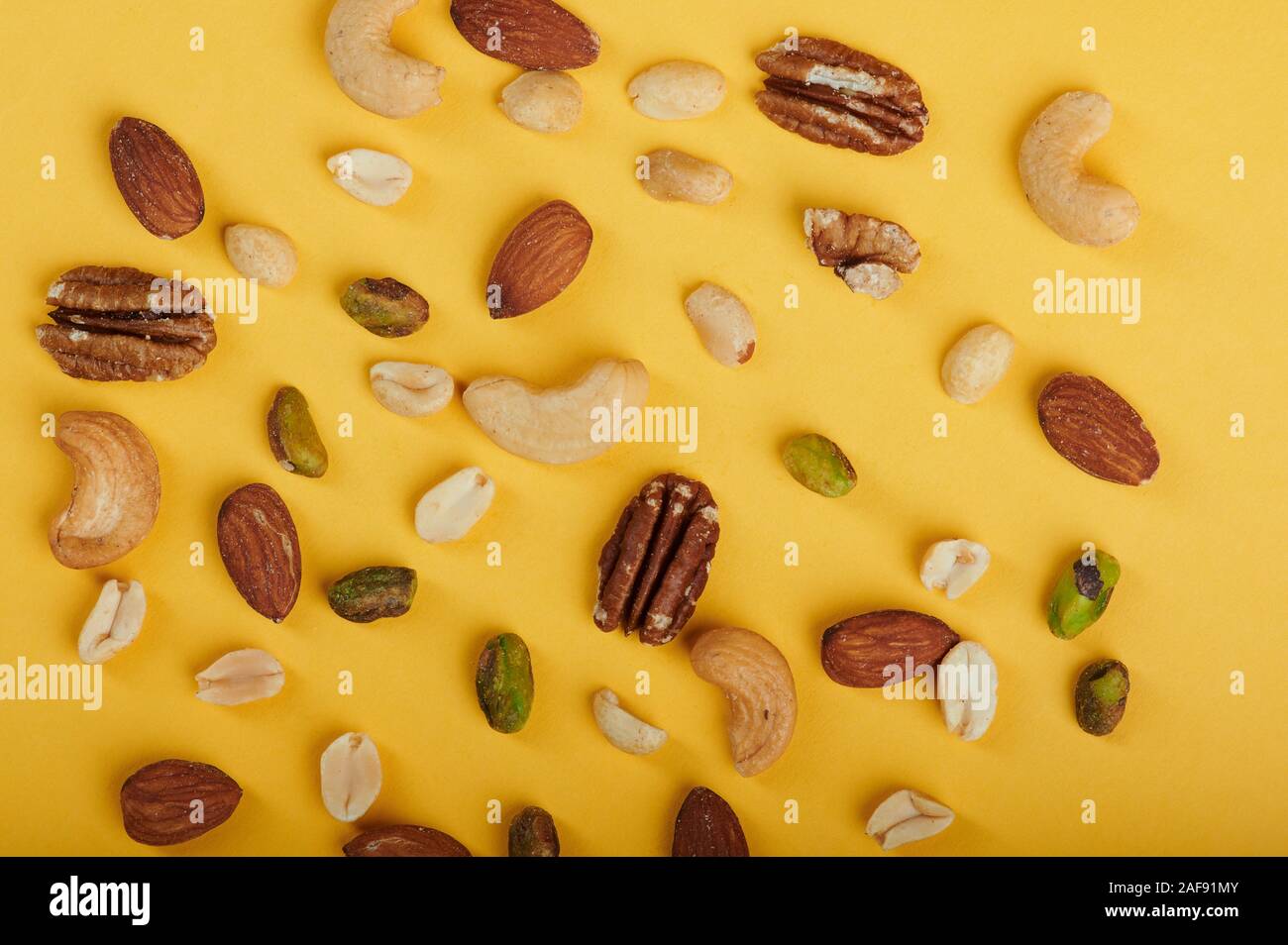 Dry nuts on yellow background above top view Stock Photo - Alamy