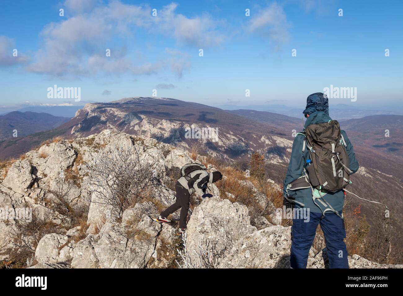 Two mountain hikers trying to pass over narrow, dangerous, slippery ...