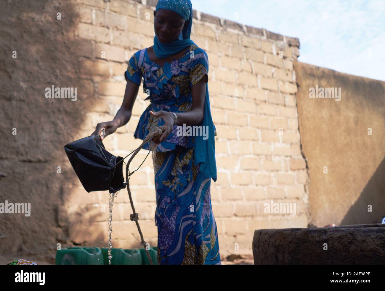 Black African Women Pouring Water into Bucket Stock Photo - Alamy