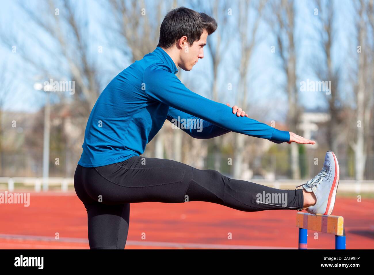 Young athlete stretching on a running track Stock Photo - Alamy