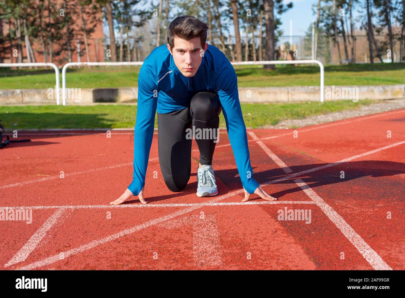 Man athlete on the starting line of a running track at the stadium ...