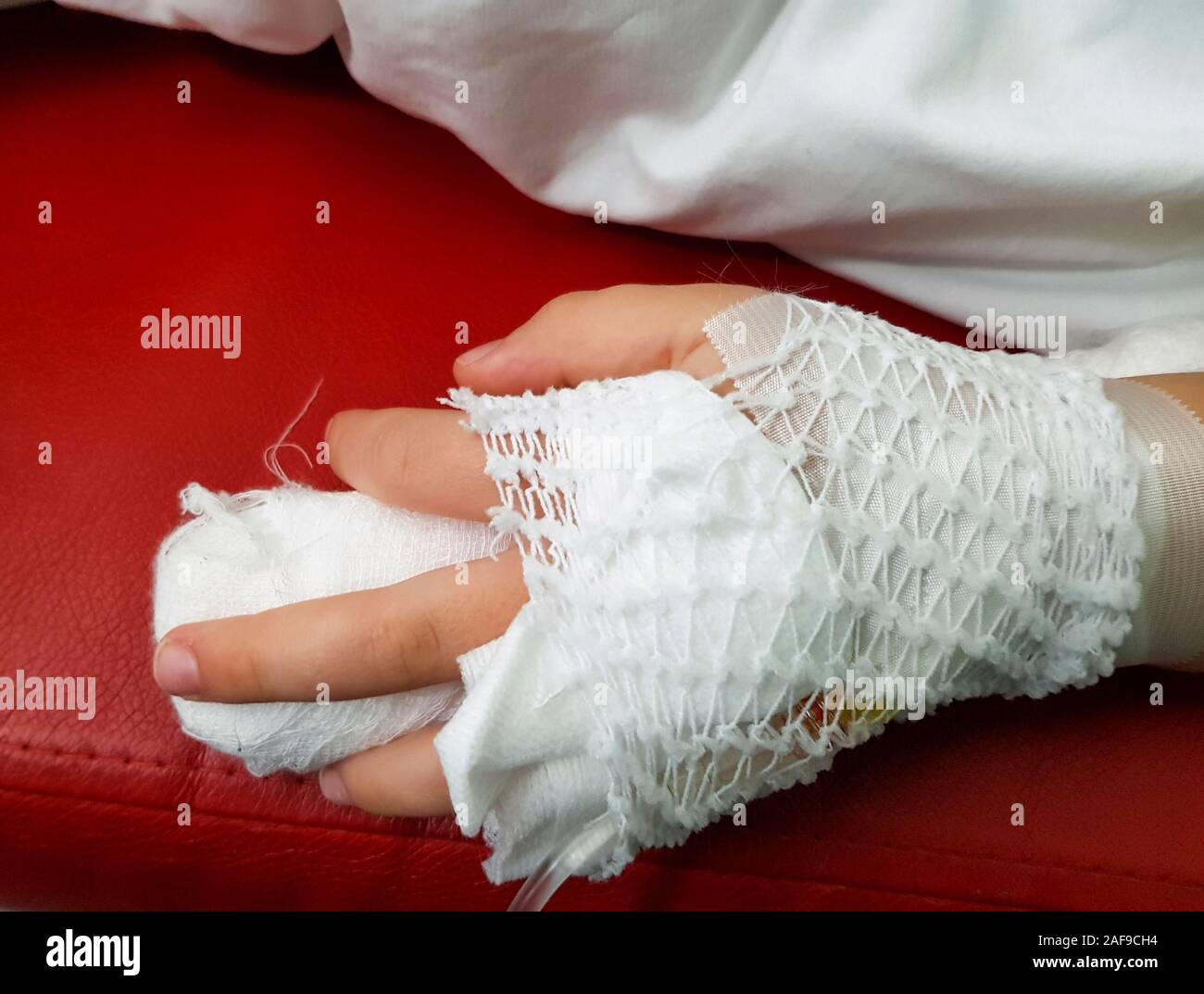 Close up infant hand with IV drip connected to upper part of gand. The ...