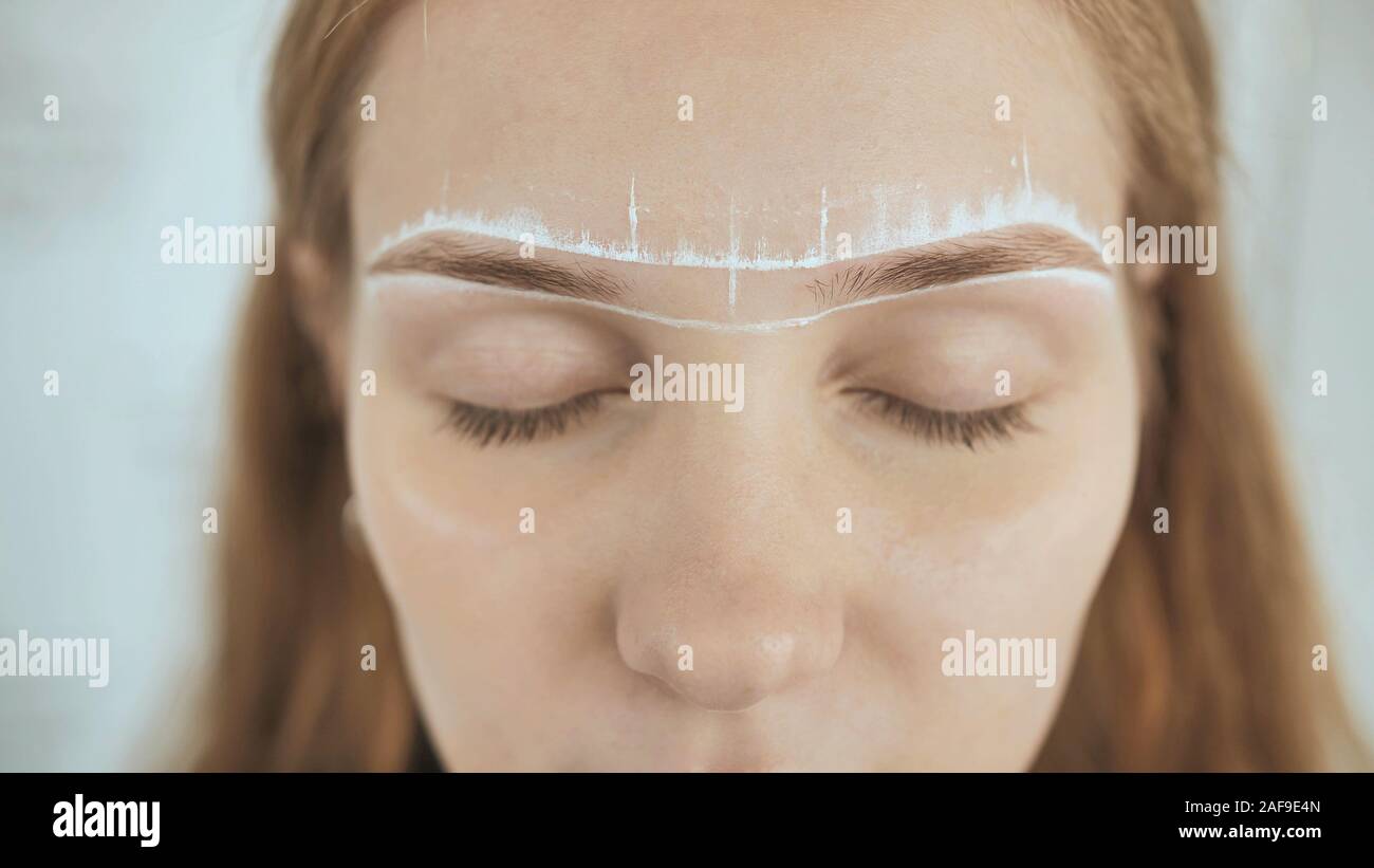 Create permanent eyebrow makeup. Marking the shape of the eyebrows ...