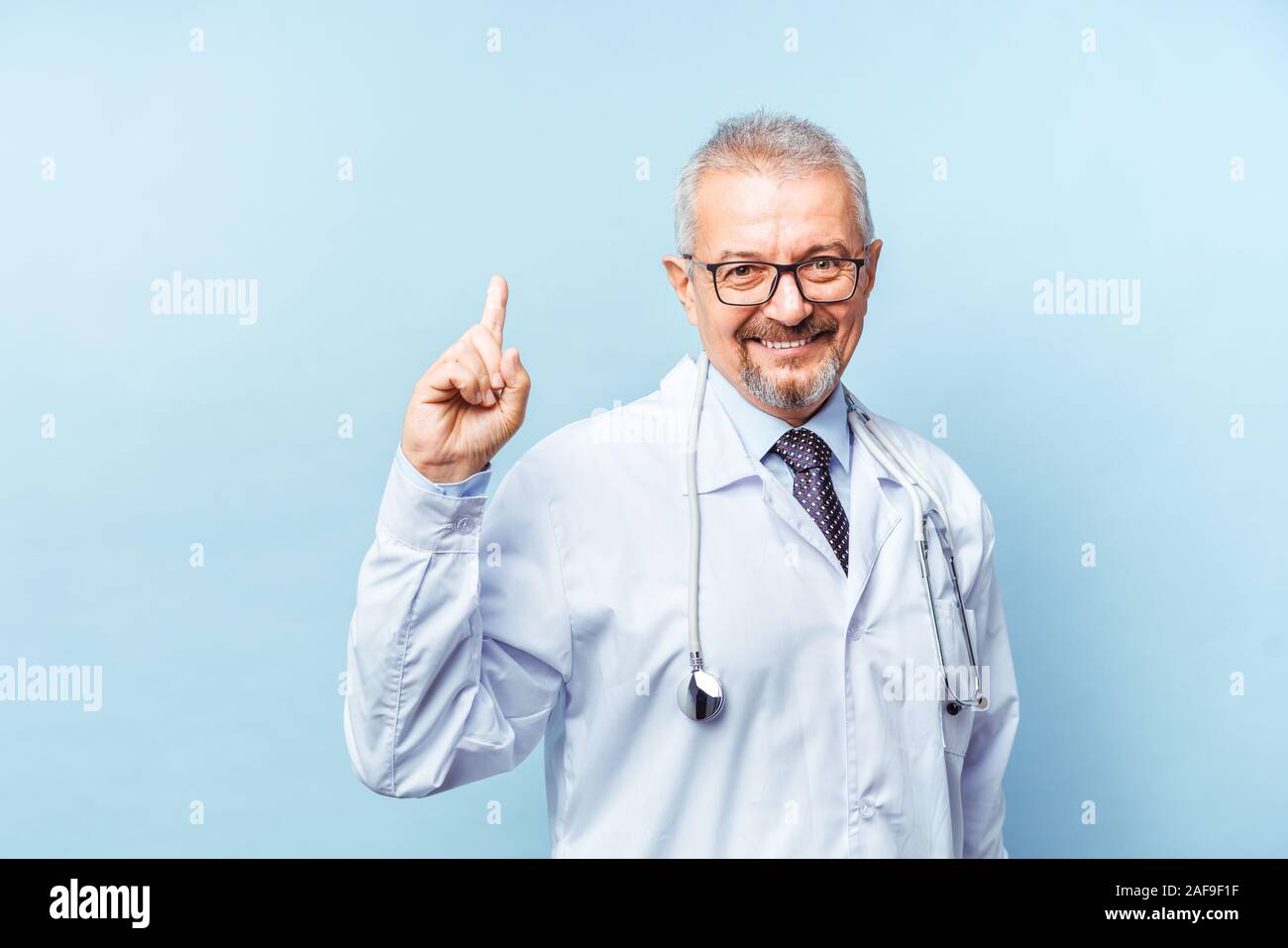 Smiling medical senior doctor with a stethoscope. On a blue background ...