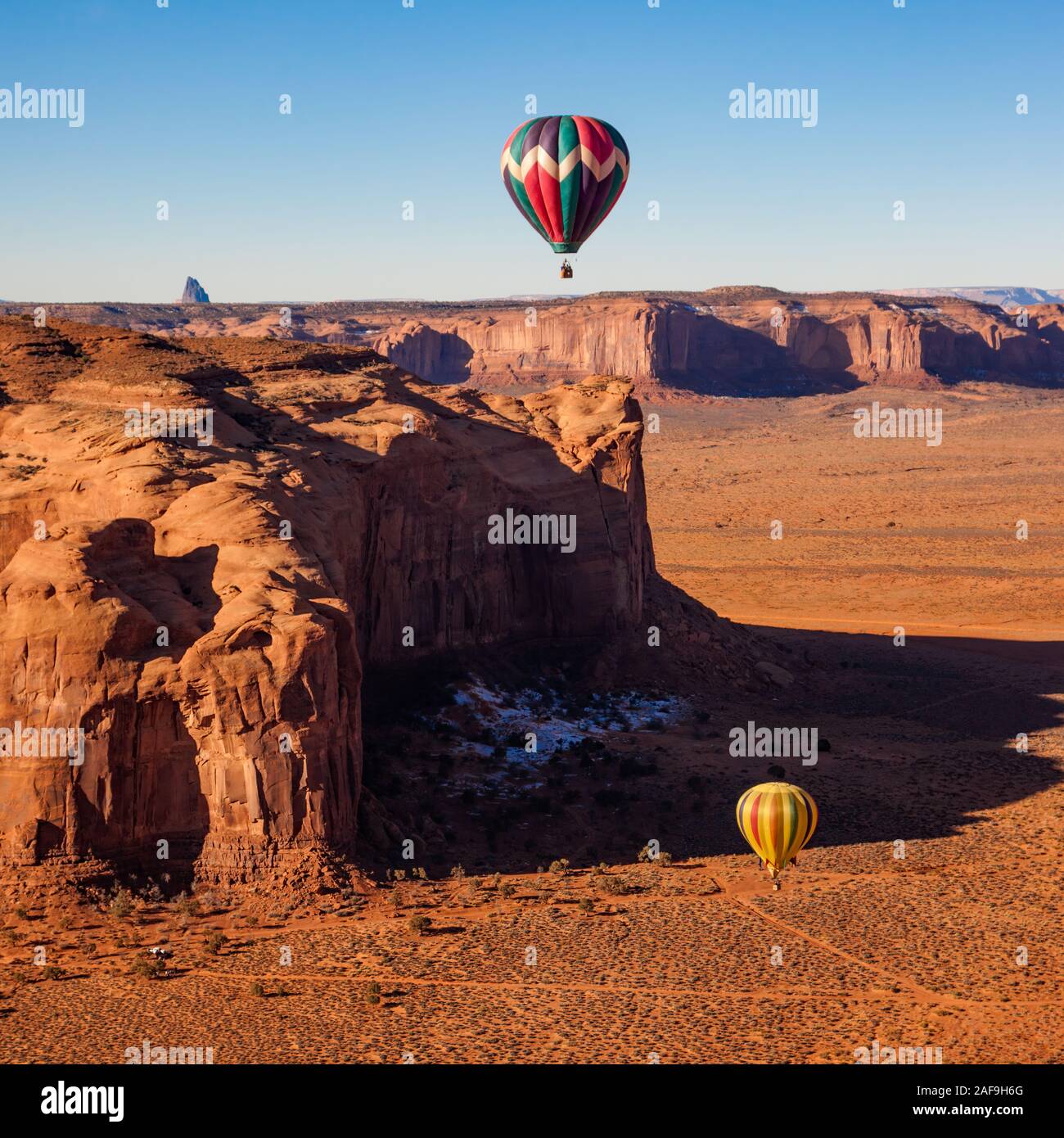 An aerial view of two hot air balloons flying by Rain God Mesa in the ...