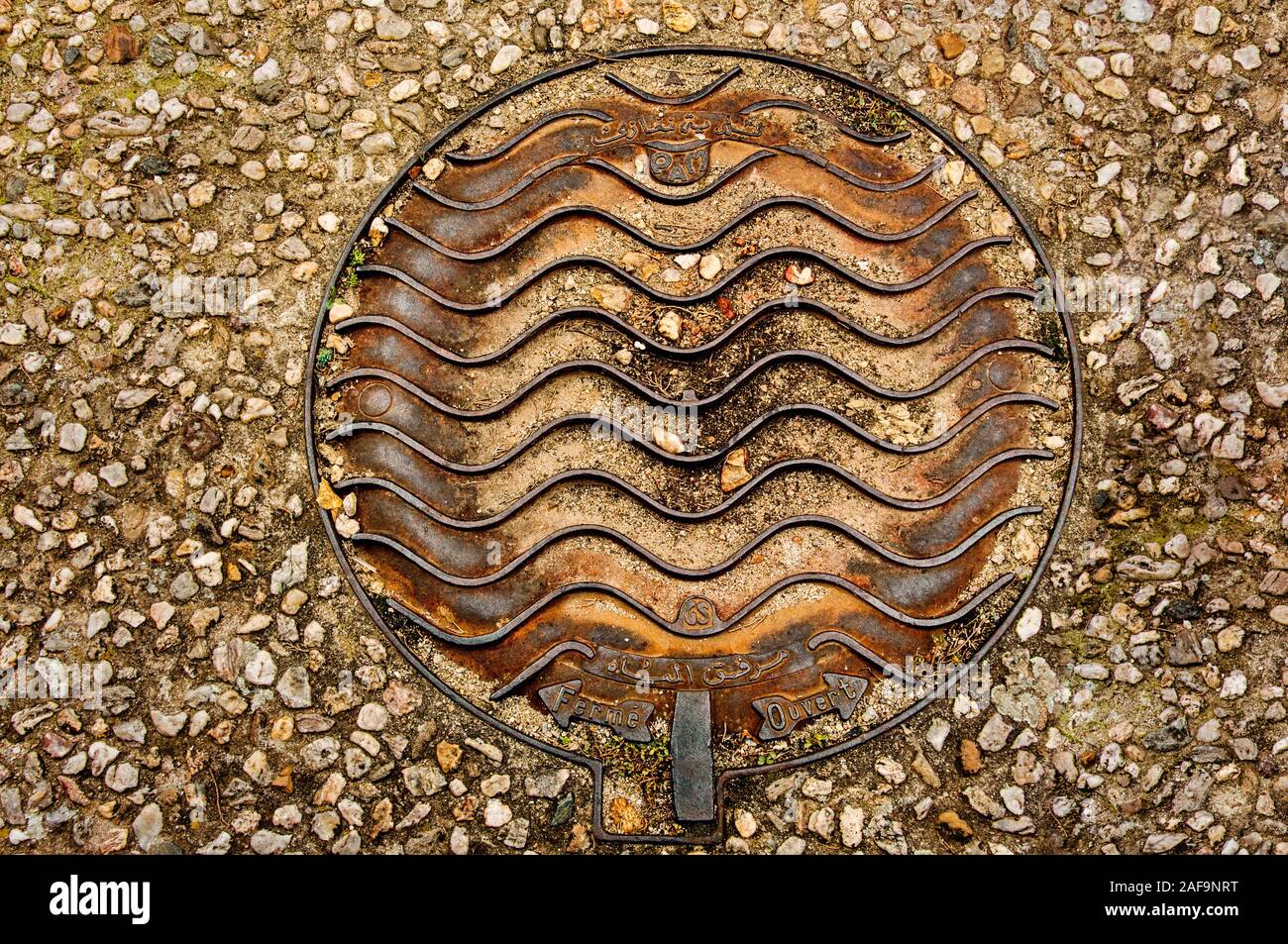 Closeup of decorative manhole cover in Najac, France, surrounded by ...