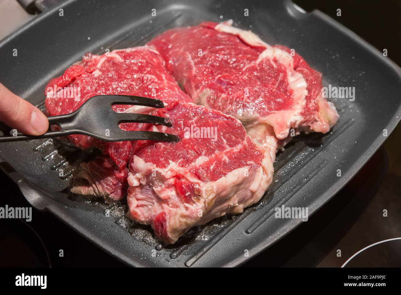 preparation of a stake from beef on frying pan Stock Photo - Alamy