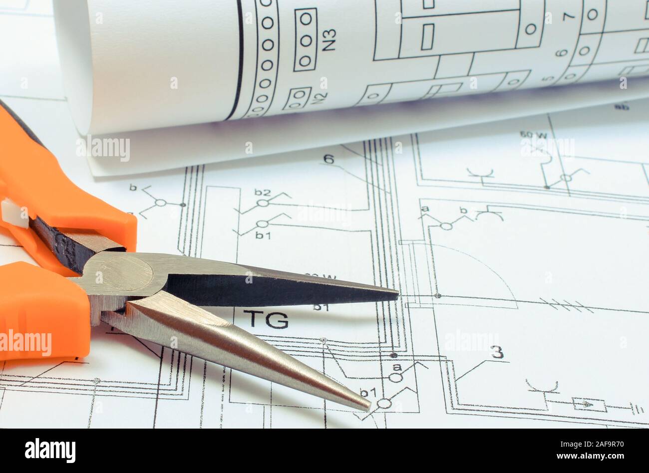 Electrical diagrams and metal pliers on construction drawing of house ...