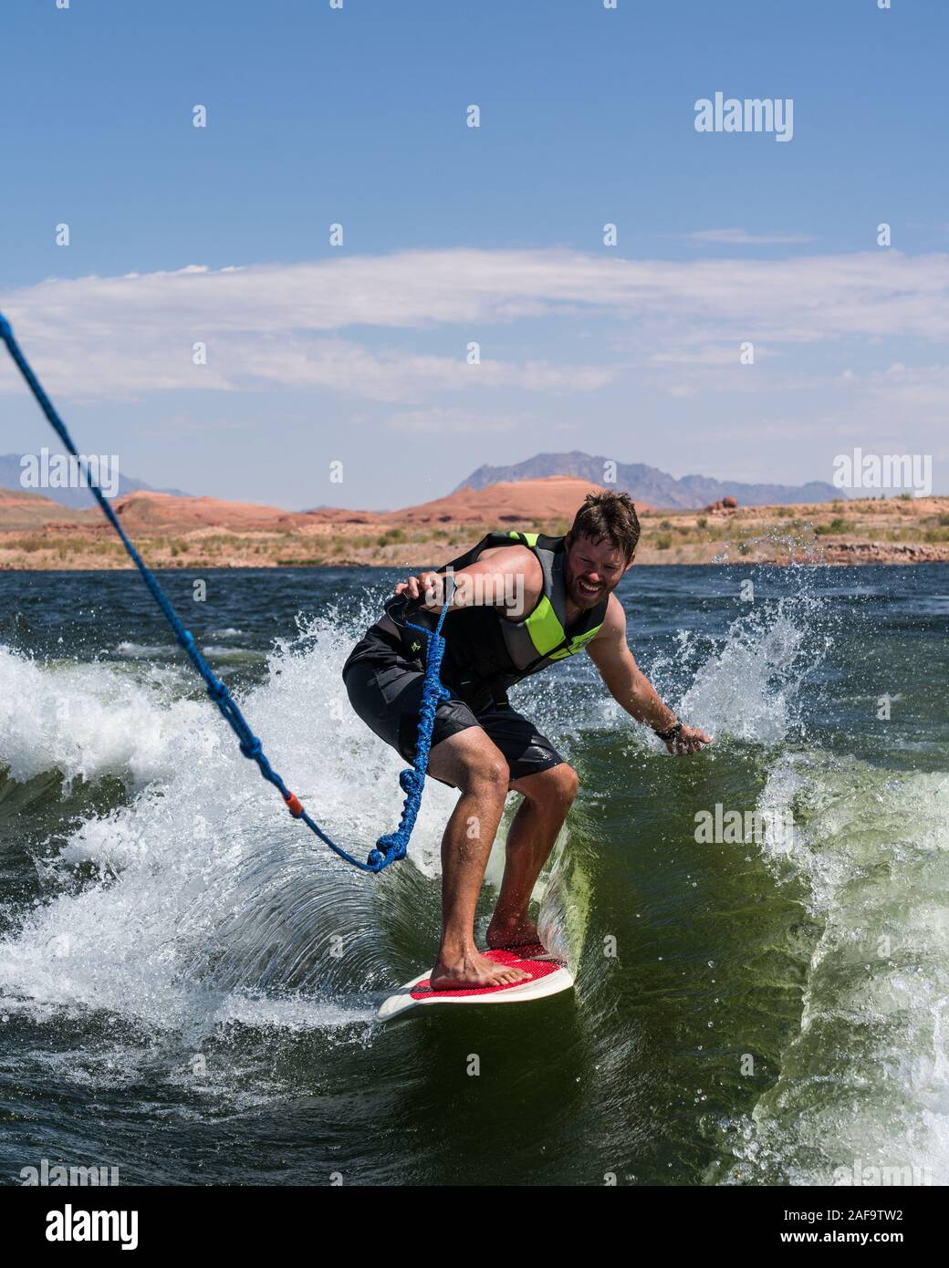 A young man wake surfing behind a boat on Lake Powell in the Glen ...