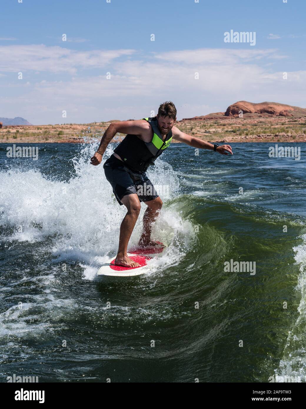 A young man wake surfing behind a boat on Lake Powell in the Glen ...
