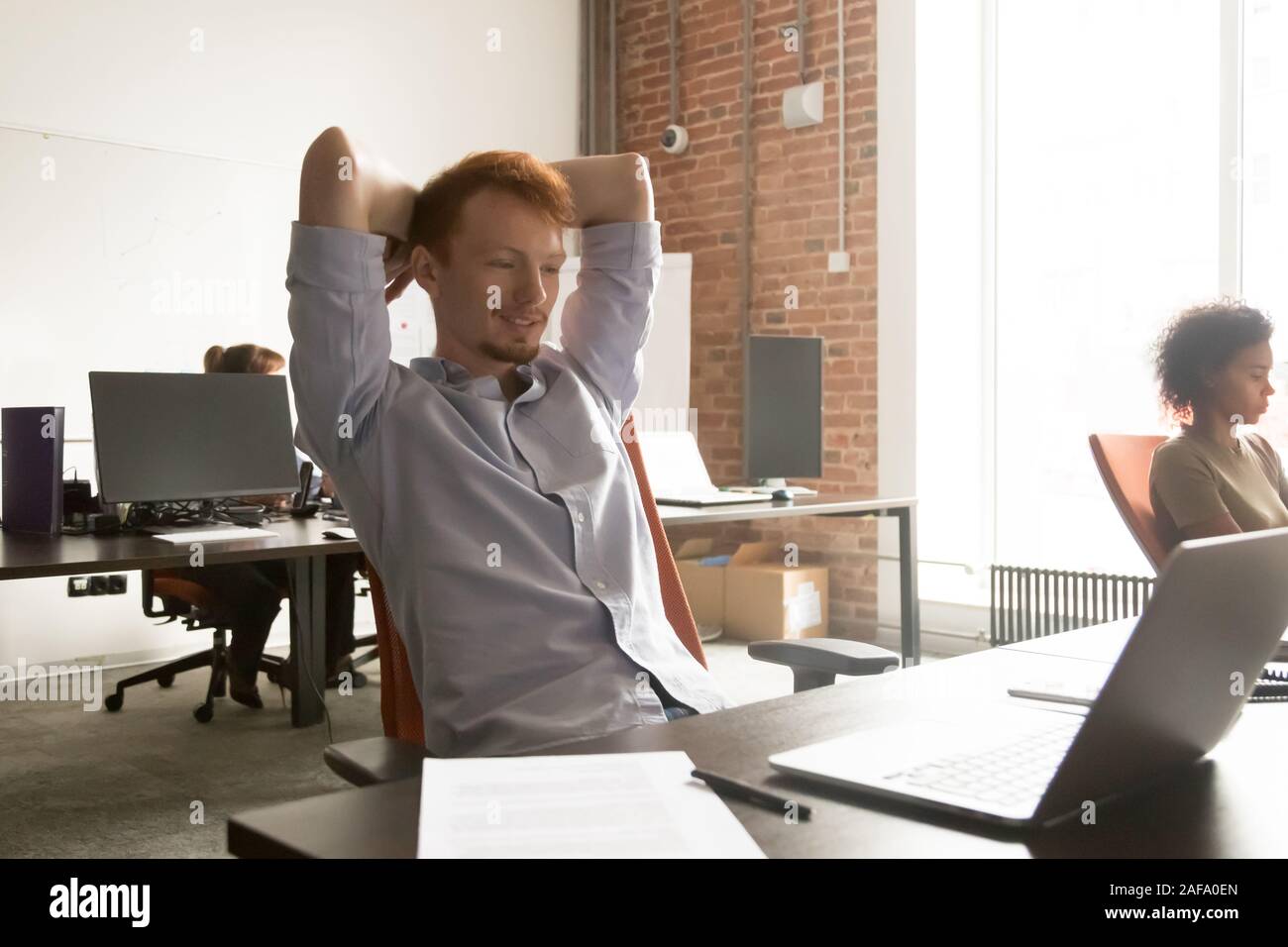 Redhead employee accomplish work relaxing sitting at shared office room ...