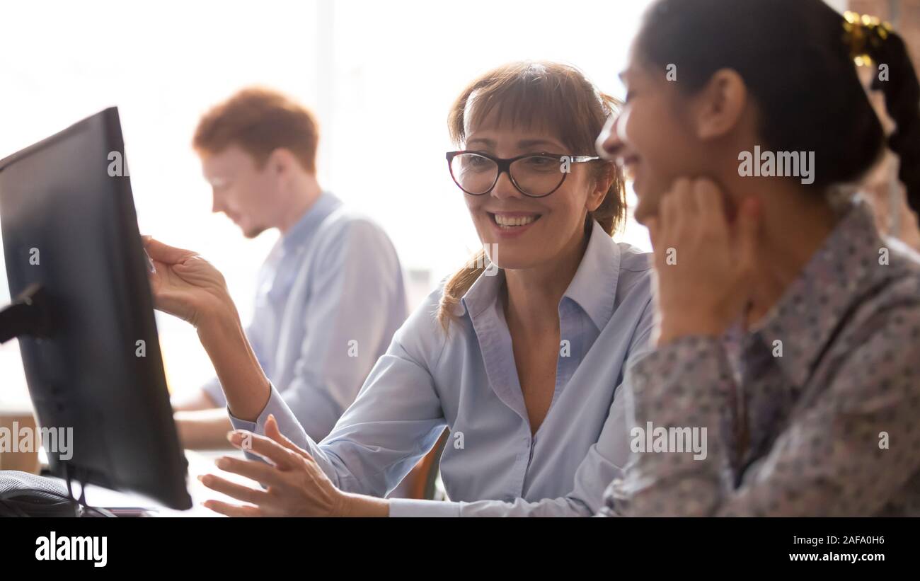 Different ages ethnicity women employees sitting at desk working ...