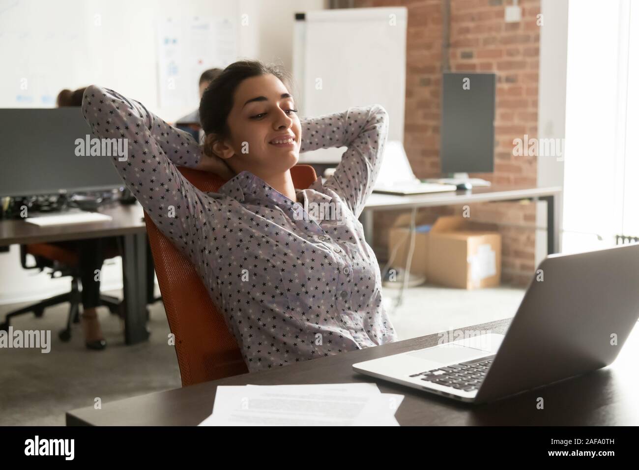 Indian ethnicity millennial employee relaxing in workplace completed ...