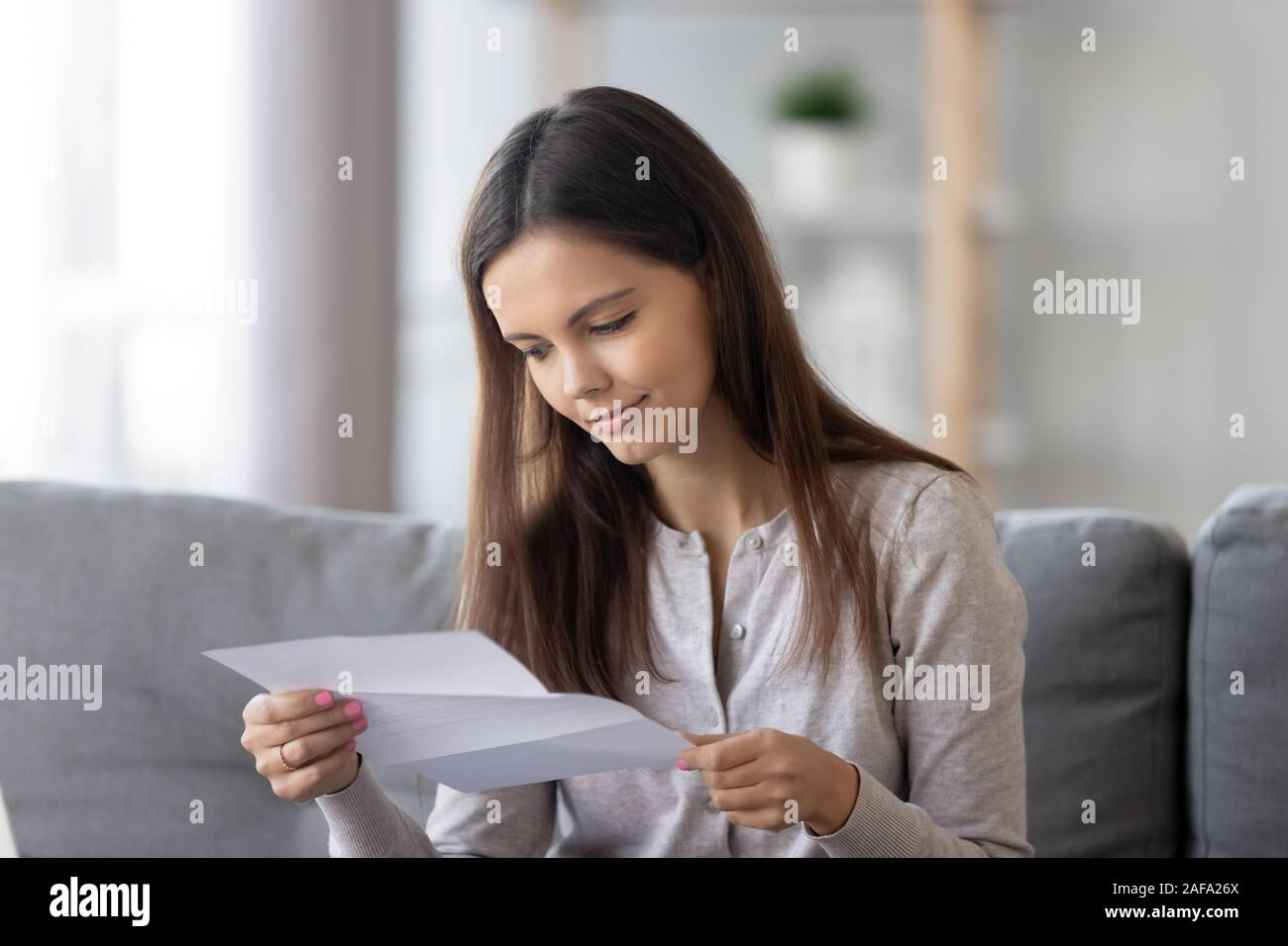 Young woman sit on couch reading paper letter Stock Photo - Alamy