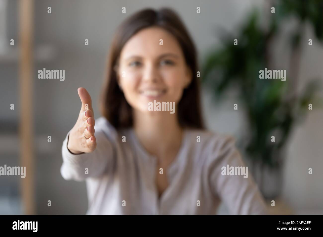 Smiling young woman stretch hand introducing at meeting Stock Photo - Alamy