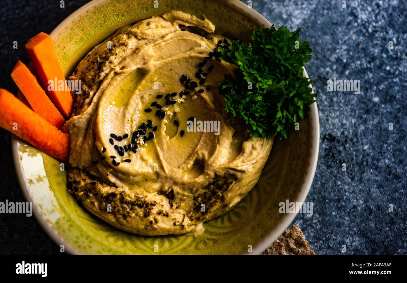 Traditional chickpeas hummus with olive oil and sesame seeds on stone ...