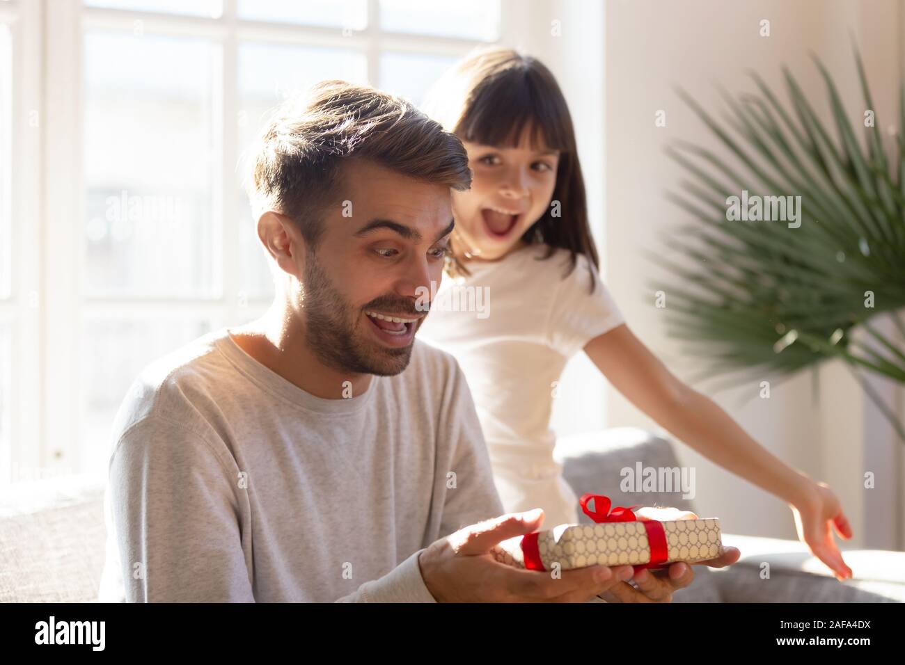 Happy father surprised by little adorable daughter unexpected gift ...