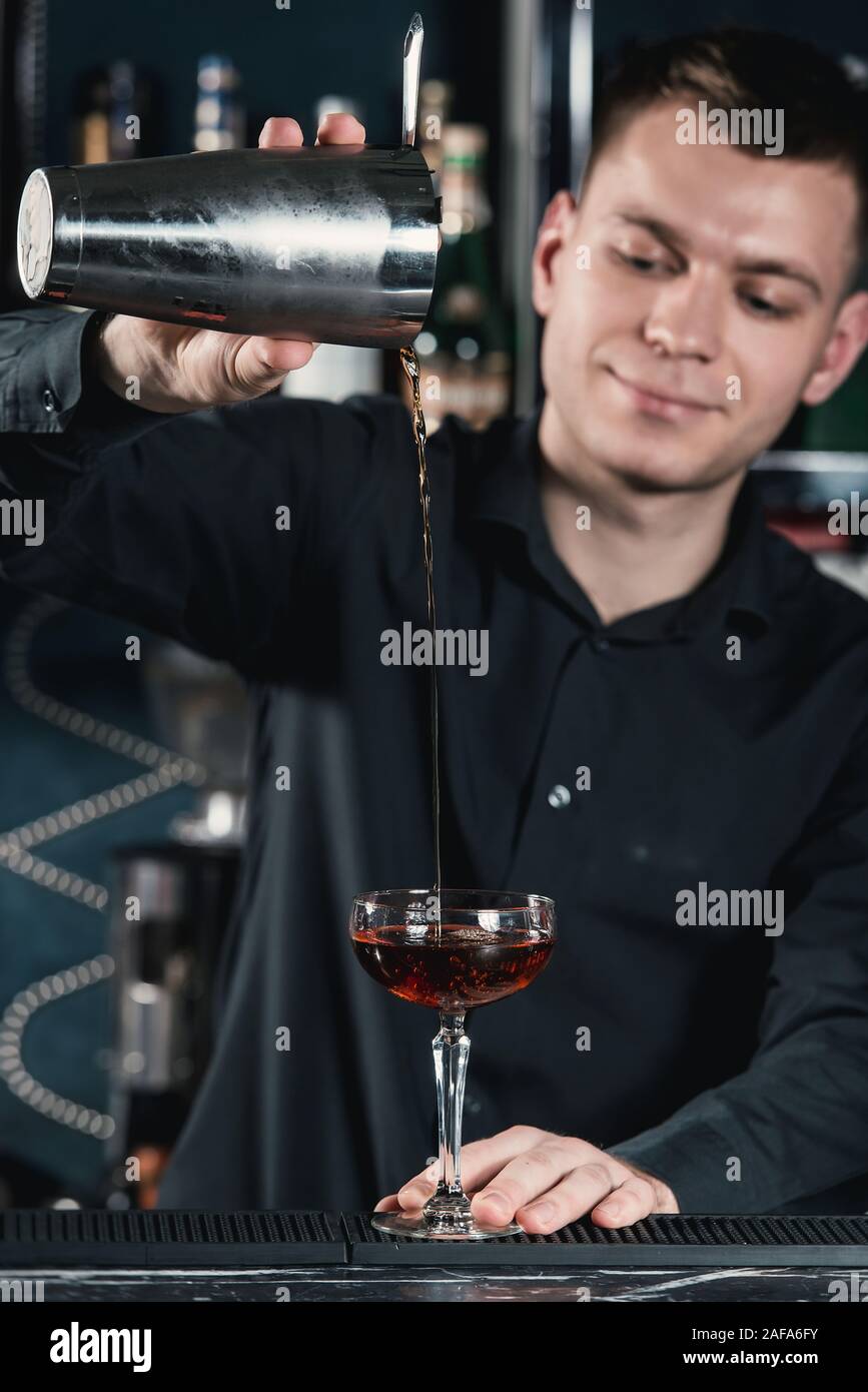 bartender making Boulevardier Cocktail pouring fluid into glass. Bar on a background Stock Photo ...