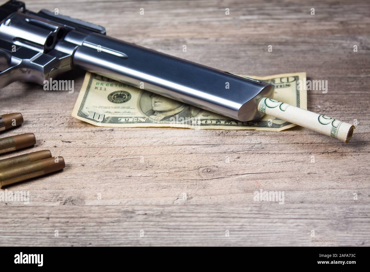 A pistol with bullets and money dollars lies on wooden the table ...