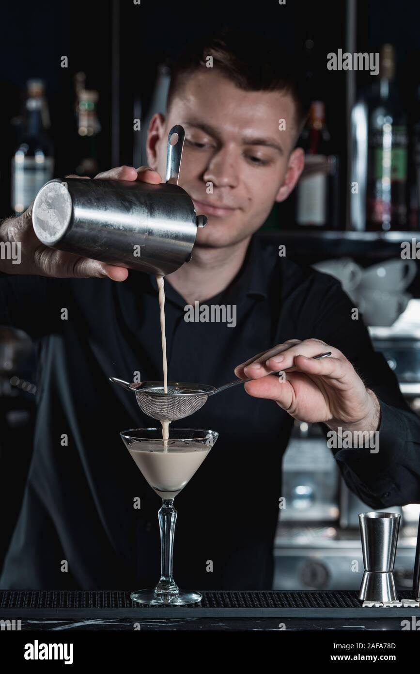 bartender making Espresso Martini cocktail, pouring fluid into glass. Bar on a background Stock ...