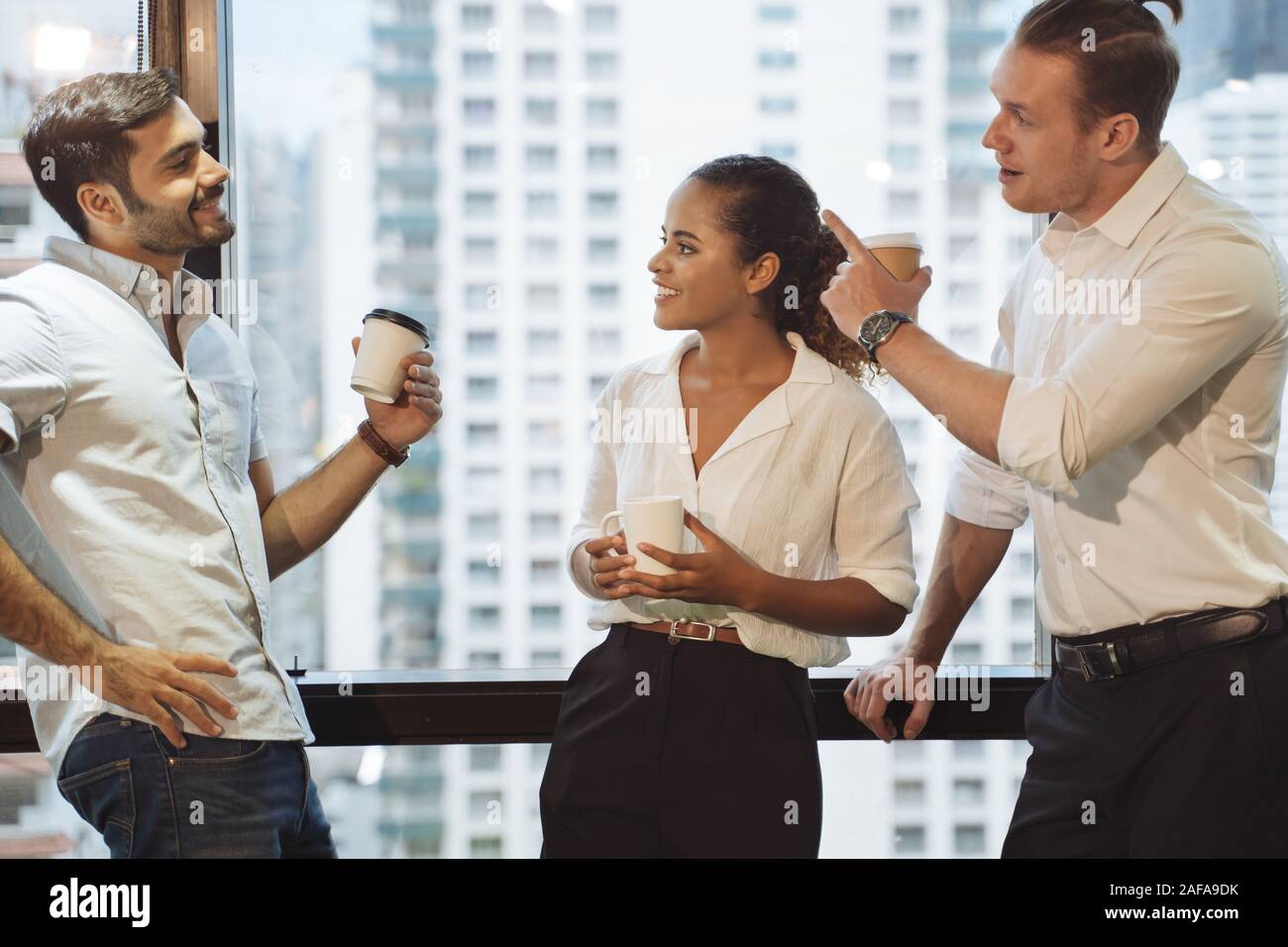Business people talking and holding cups of coffee with city view ...