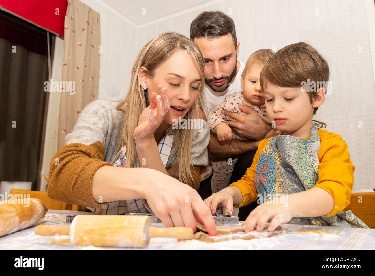 Young family with two children making gingerbread cookies in the ...