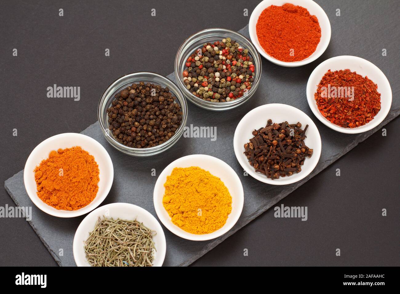 Colorful various ground spices, dry cloves and herbs in porcelain bowls ...