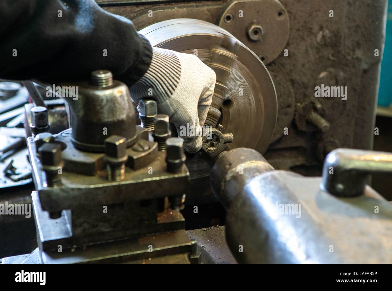Close-up of hand in glove and lathe. Thread cutting on a stud ...
