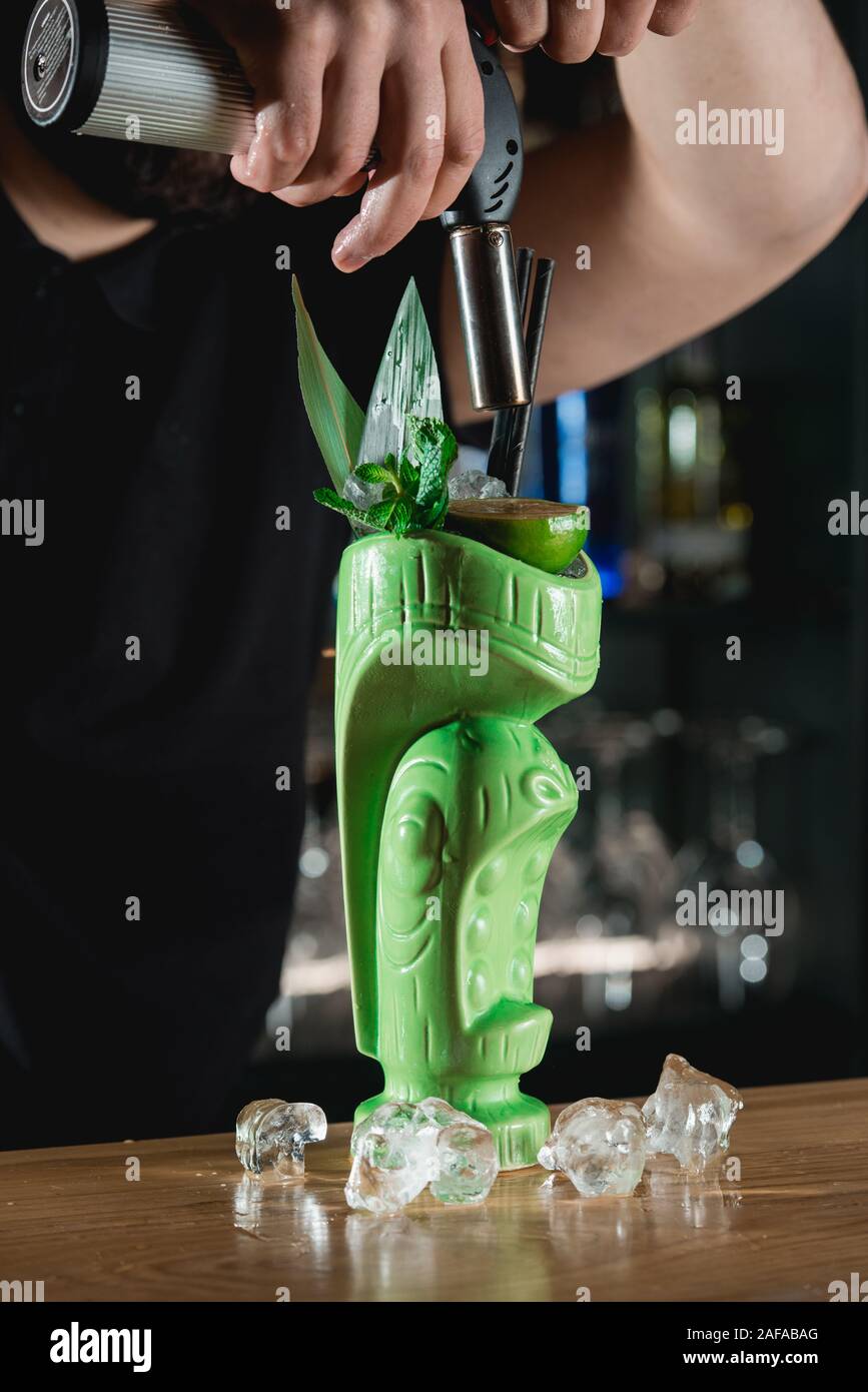 Bartender maiking tropical cocktail served in a tiki style glass and ...
