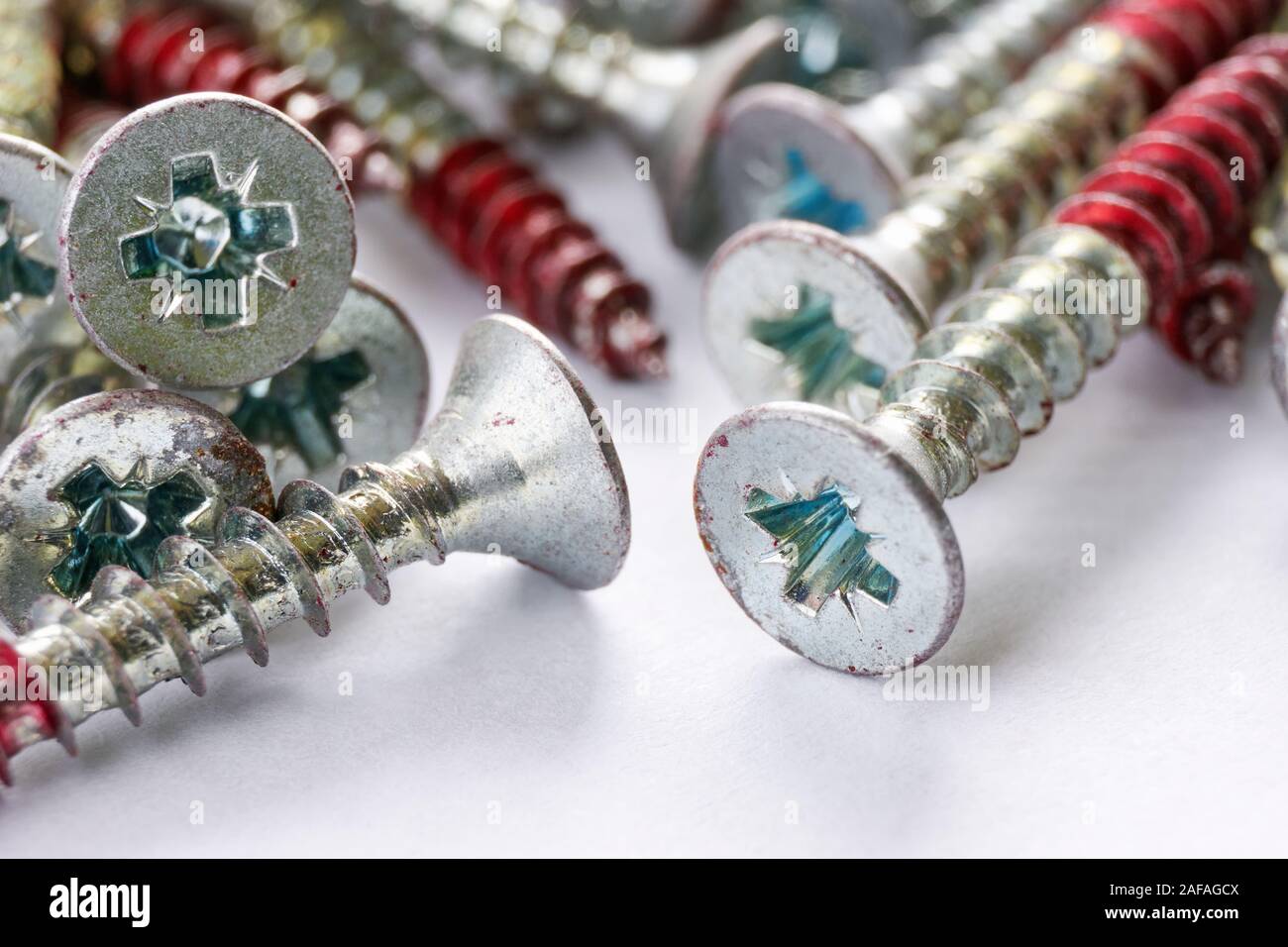 Close-up of many old crosshead screws with red lubrication tip on white ...