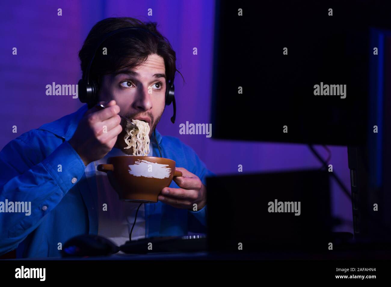 Male gamer eating noodle soup, playing video games Stock Photo - Alamy