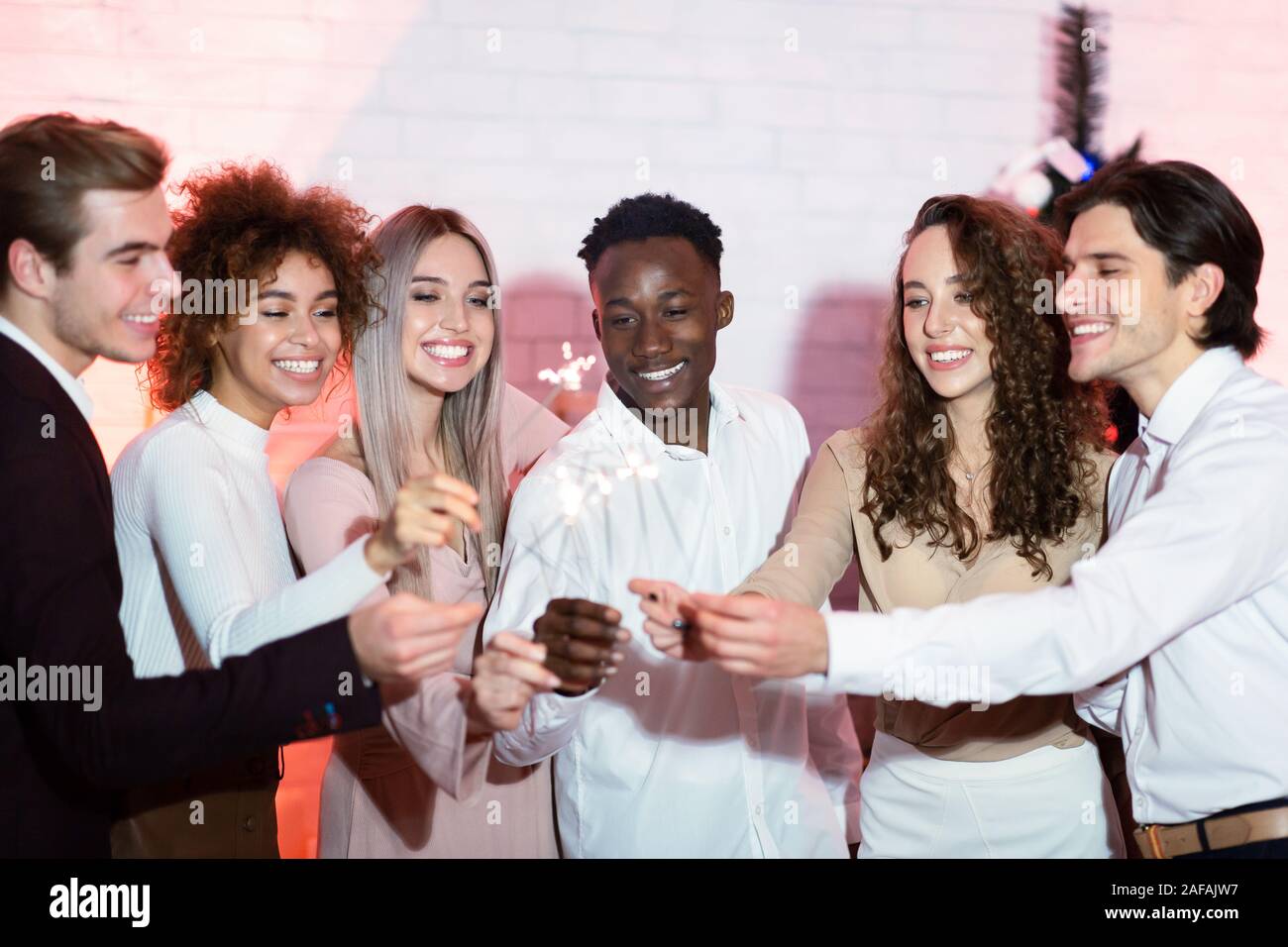 Group Of Friends Holding Sparklers Celebrating New Year Standing Indoor ...