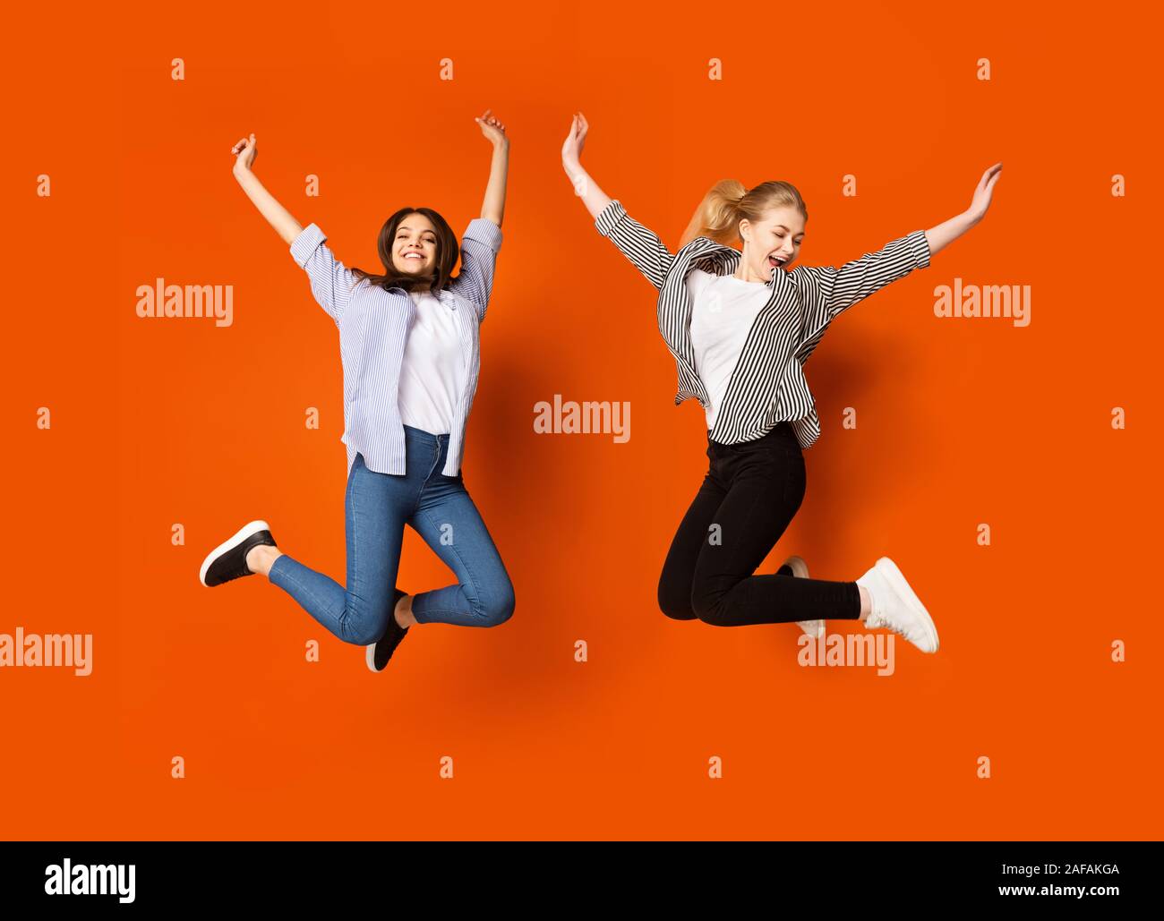 Friendship concept. Cute teen girls jumping in studio Stock Photo - Alamy