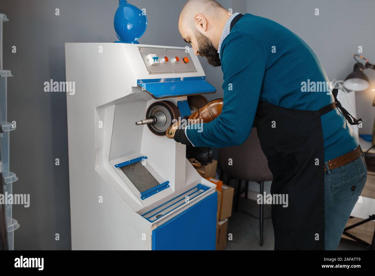 Shoemaker processes the shoe on emery machine Stock Photo - Alamy