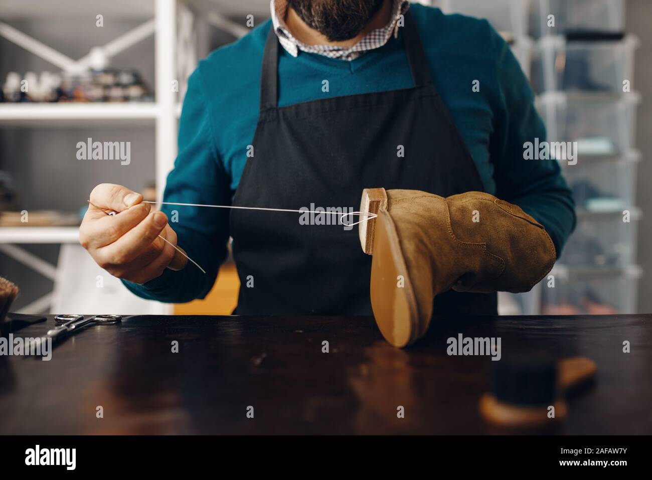 Shoemaker stitches the shoe, footwear repair Stock Photo - Alamy