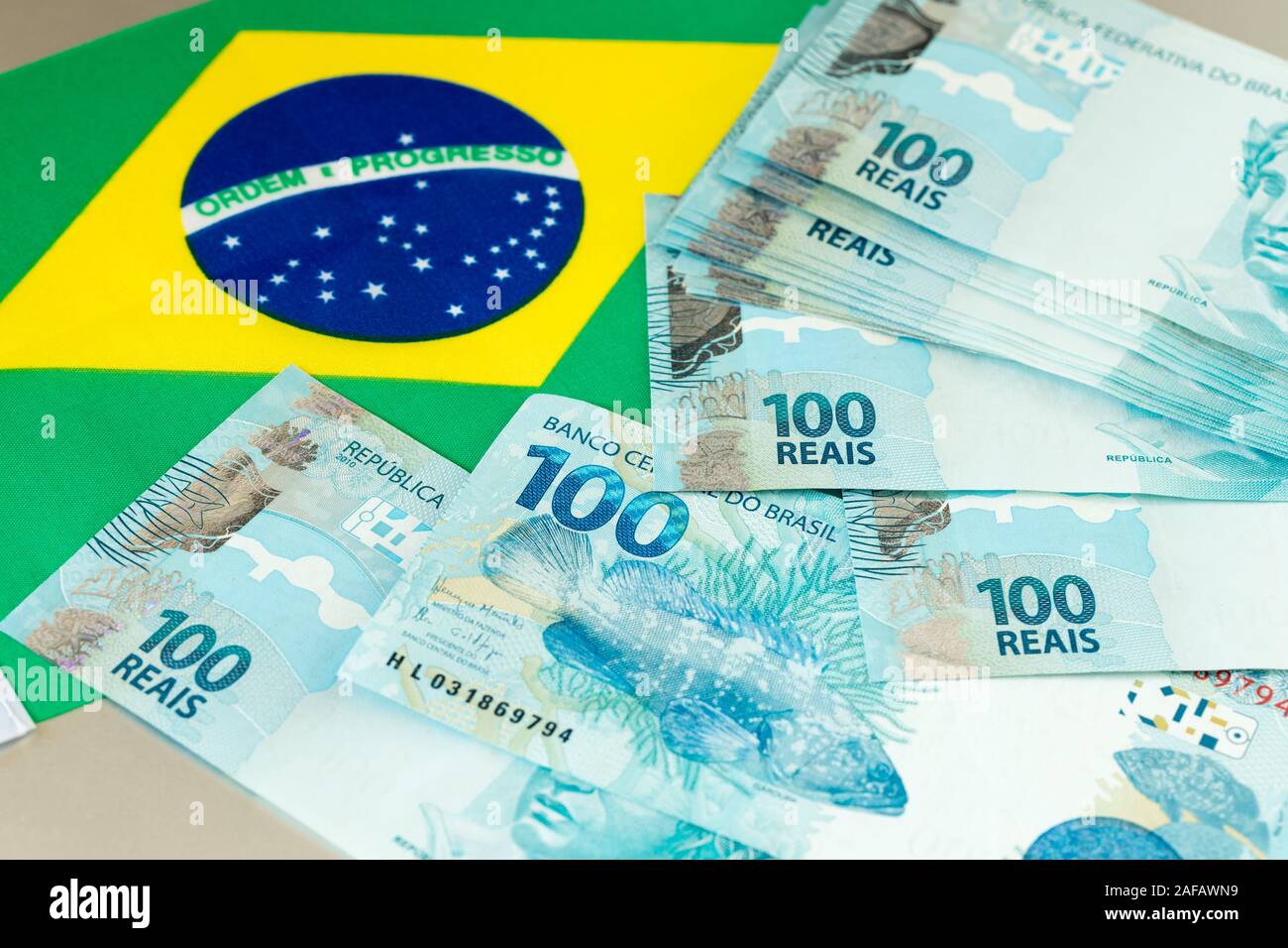 Brazilian money banknotes on the background of the flag of the country ...