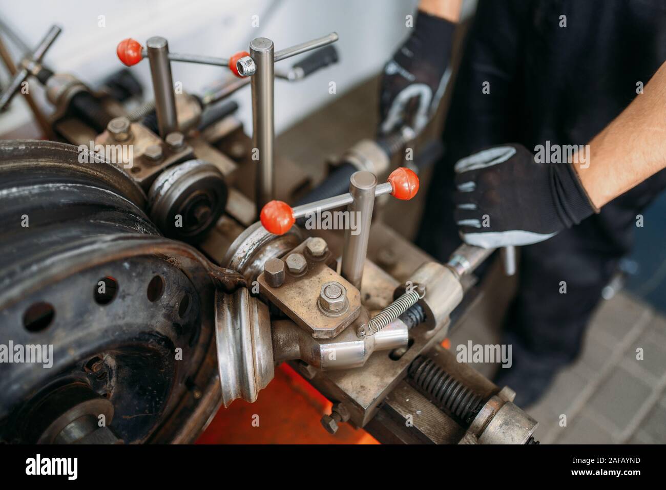 Mechanic works with wheel on disc rolling machine Stock Photo - Alamy