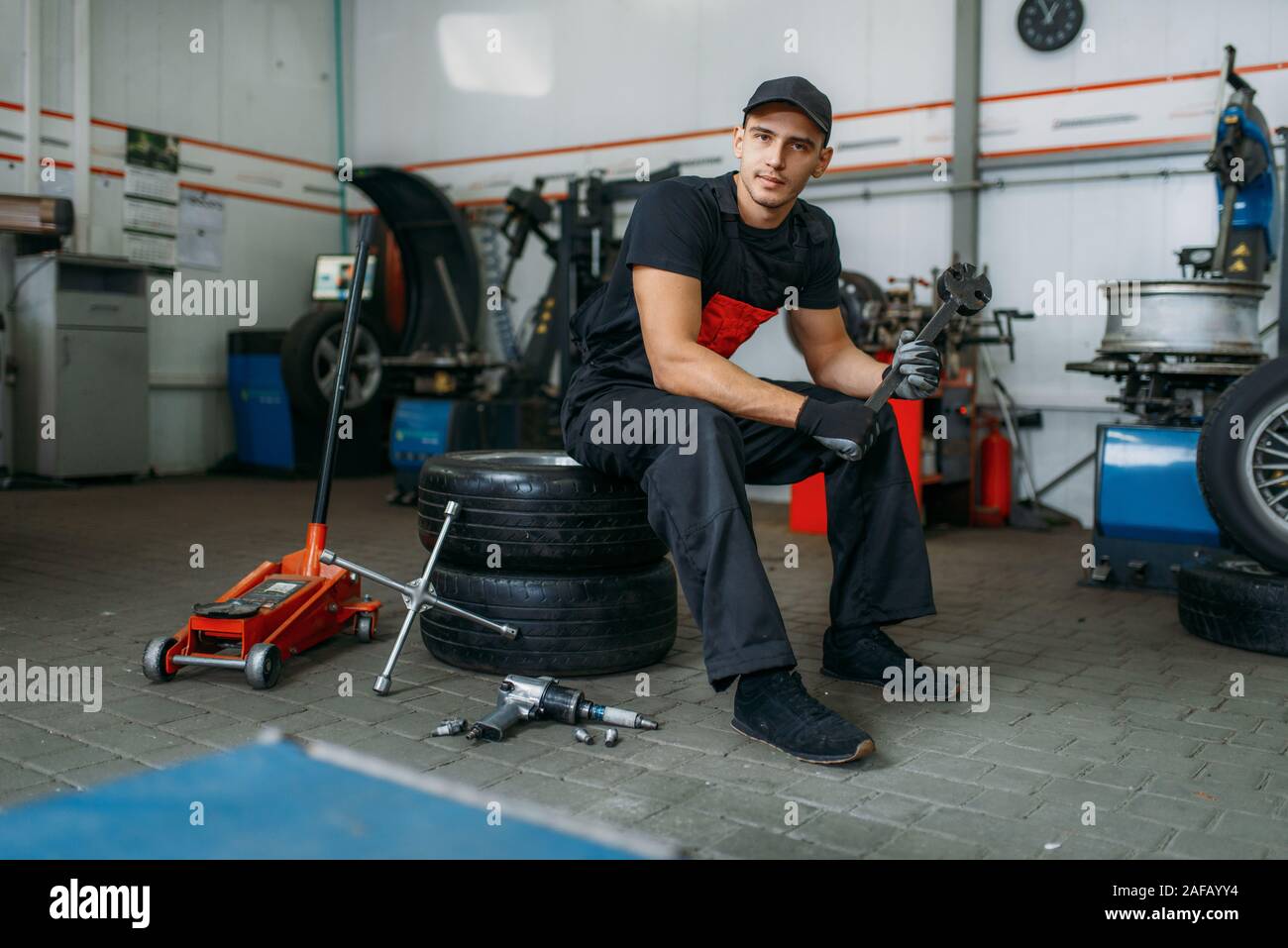 Auto mechanic sitting on wheels, tire service Stock Photo - Alamy