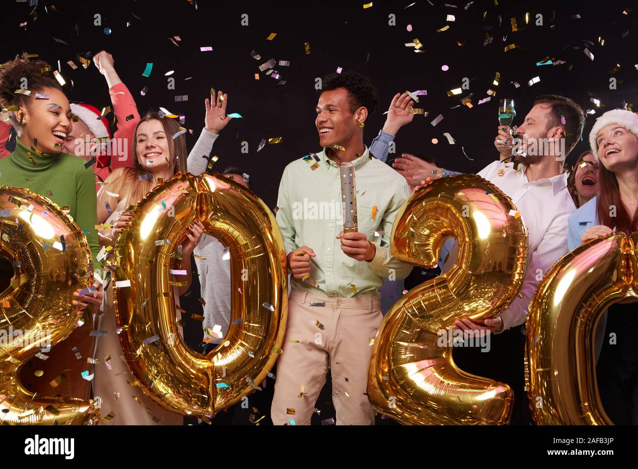Happy New Year. Group of happy multiethnic people holding gold colored ...