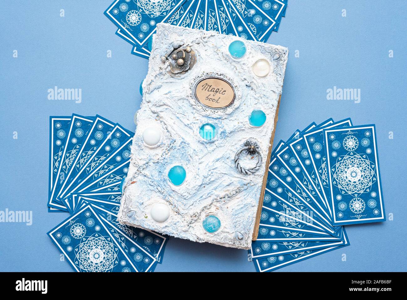 Magic book and tarot cards on blue flat lay background Stock Photo - Alamy