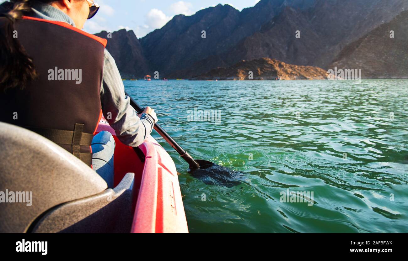 Woman kayaking in a scenic lake surrounded by mountains , active ...