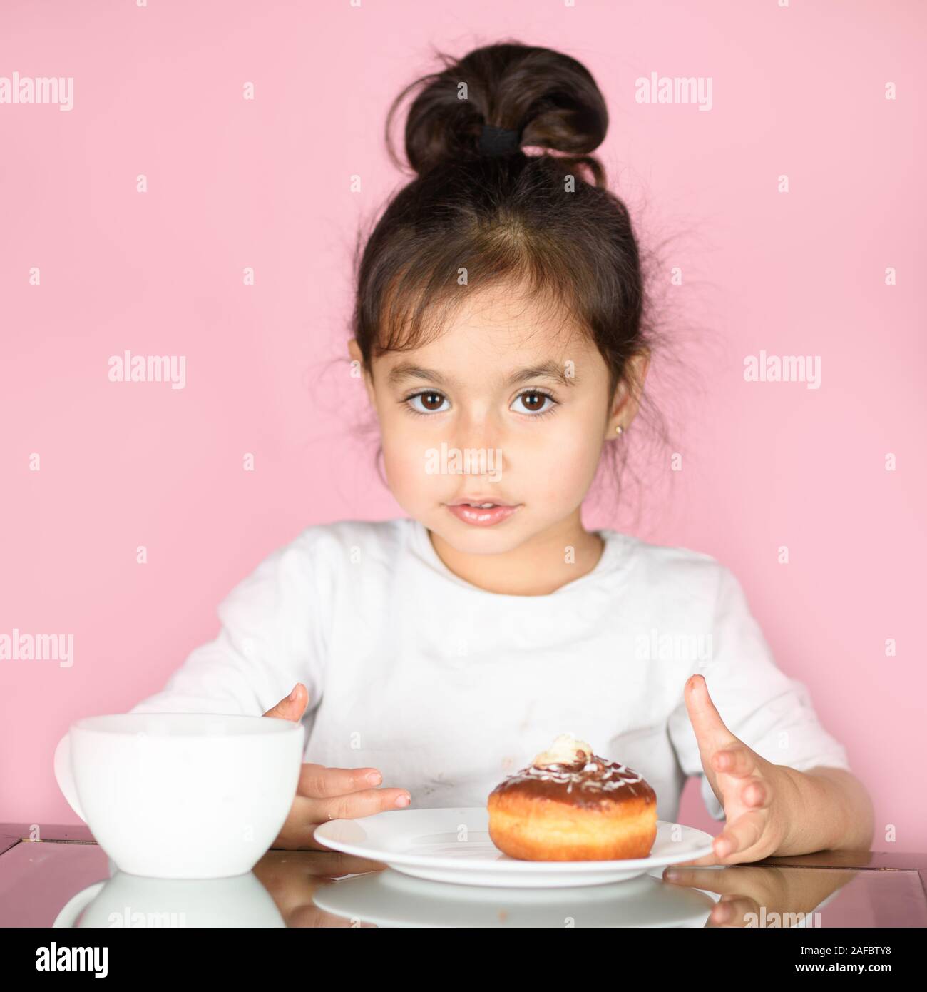 Little happy cute girl eating donut and drinking tea. Selective focus ...