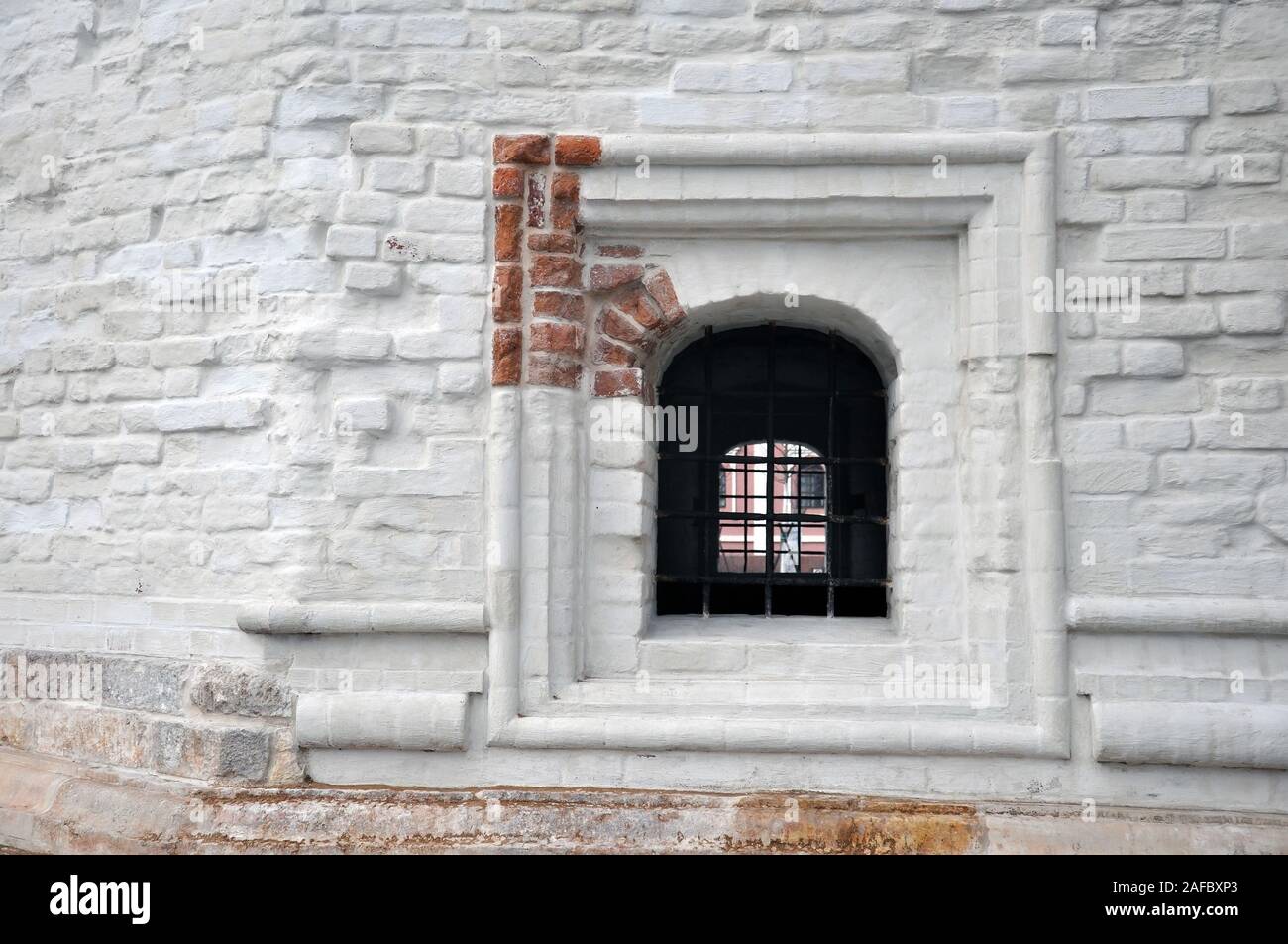 Window with bars in the old brick wall of the church. Russian ...