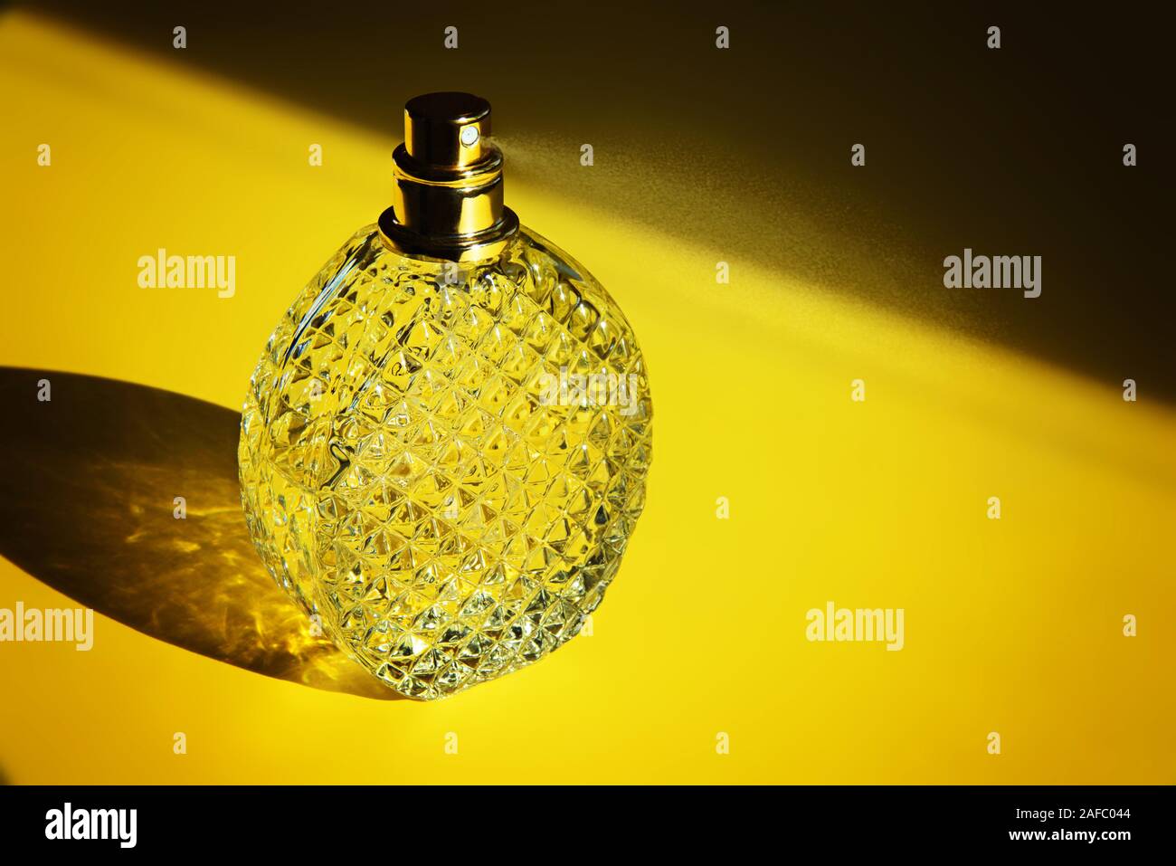 Bottle of perfume on bright yellow background with contrast of light ...