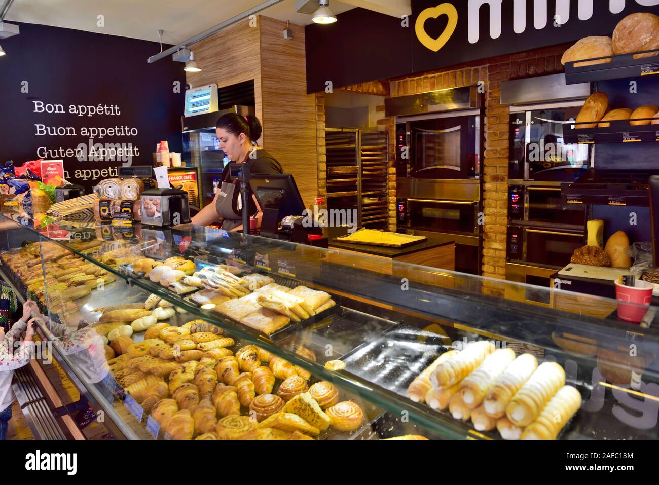Inside bakery (Mlinar) with small child looking up at pastries on offer ...