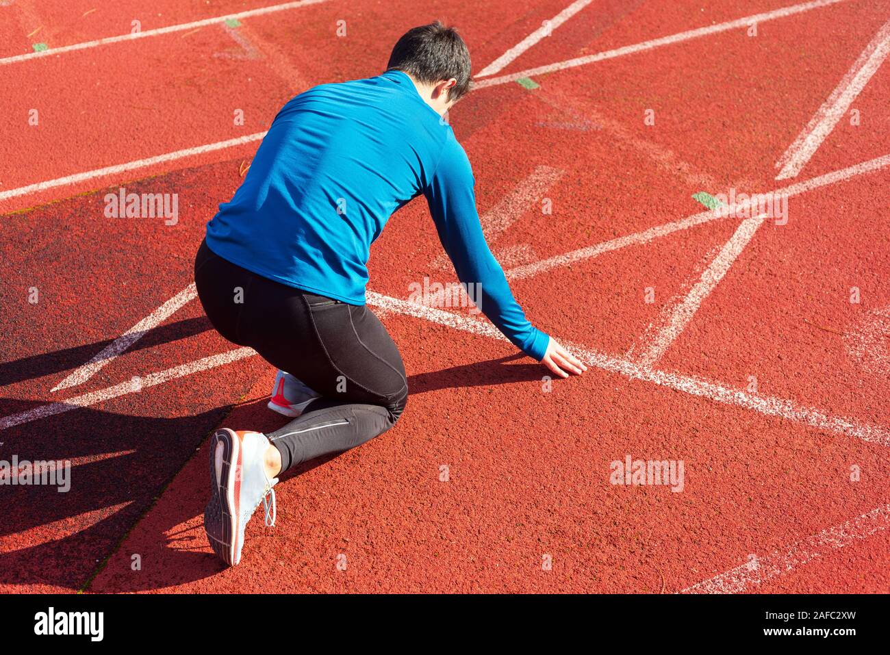 Man athlete on the starting line of a running track at the stadium ...