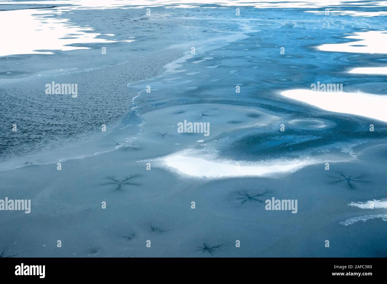 Lake frozen in early winter, part of the flat water surface are covered ...